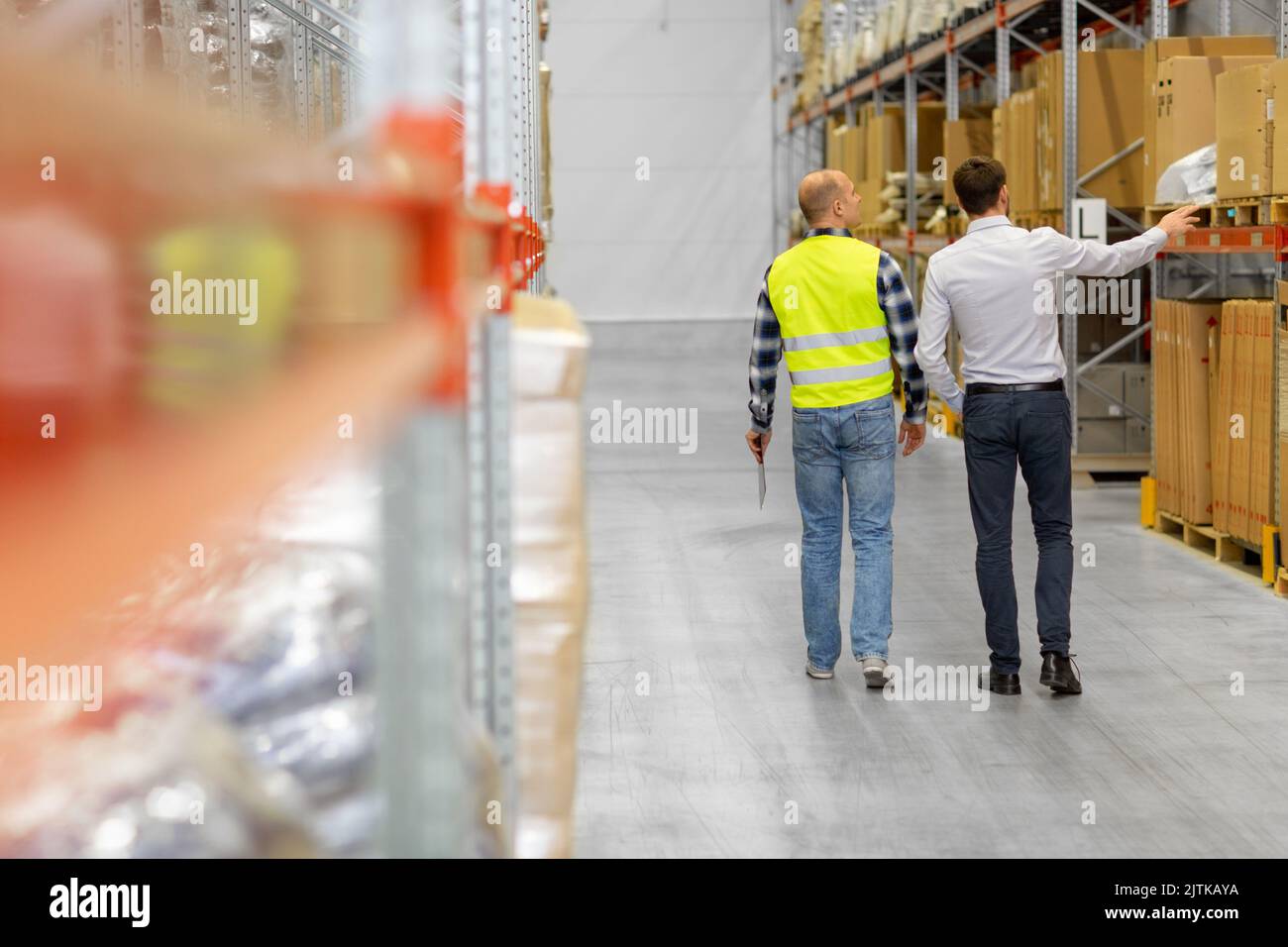 worker and businessman walking along warehouse Stock Photo - Alamy