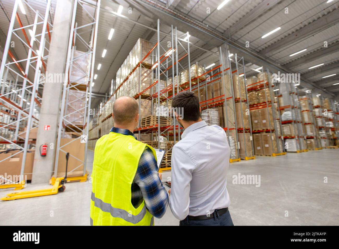 businessman showing warehouse to worker Stock Photo - Alamy