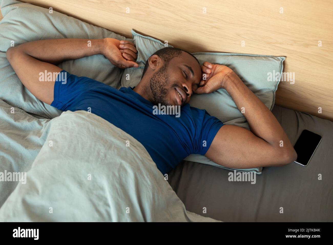 African American Man Sleeping Well Stretching Arms Lying In Bedroom ...