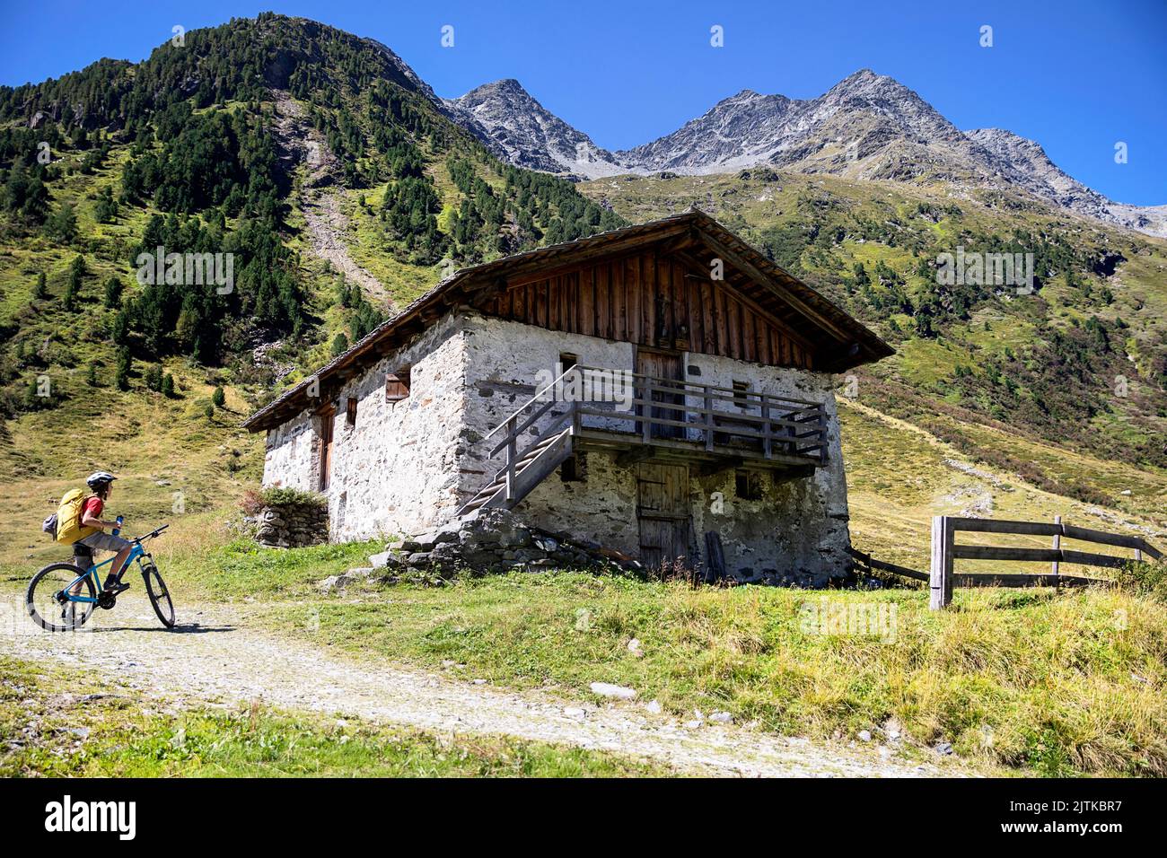 Boy on a mountain bike resting near a traditional alpine austrian house ...