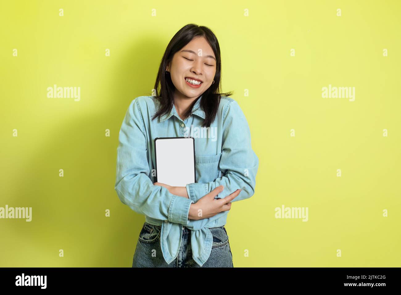 Happy Japanese Female Hugging Digital Tablet Posing Over Yellow ...
