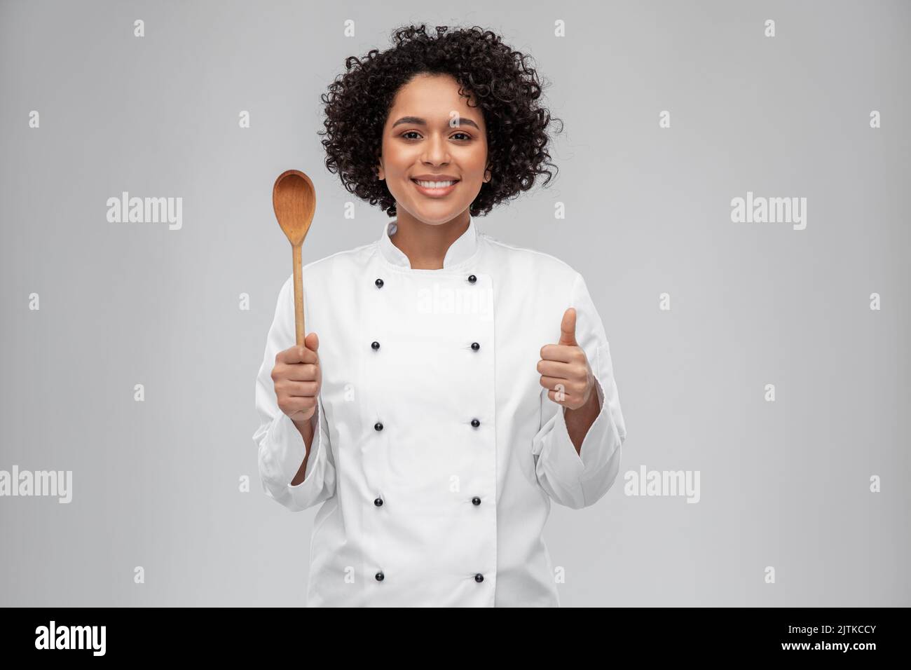 smiling female chef with spoon showing thumbs up Stock Photo - Alamy