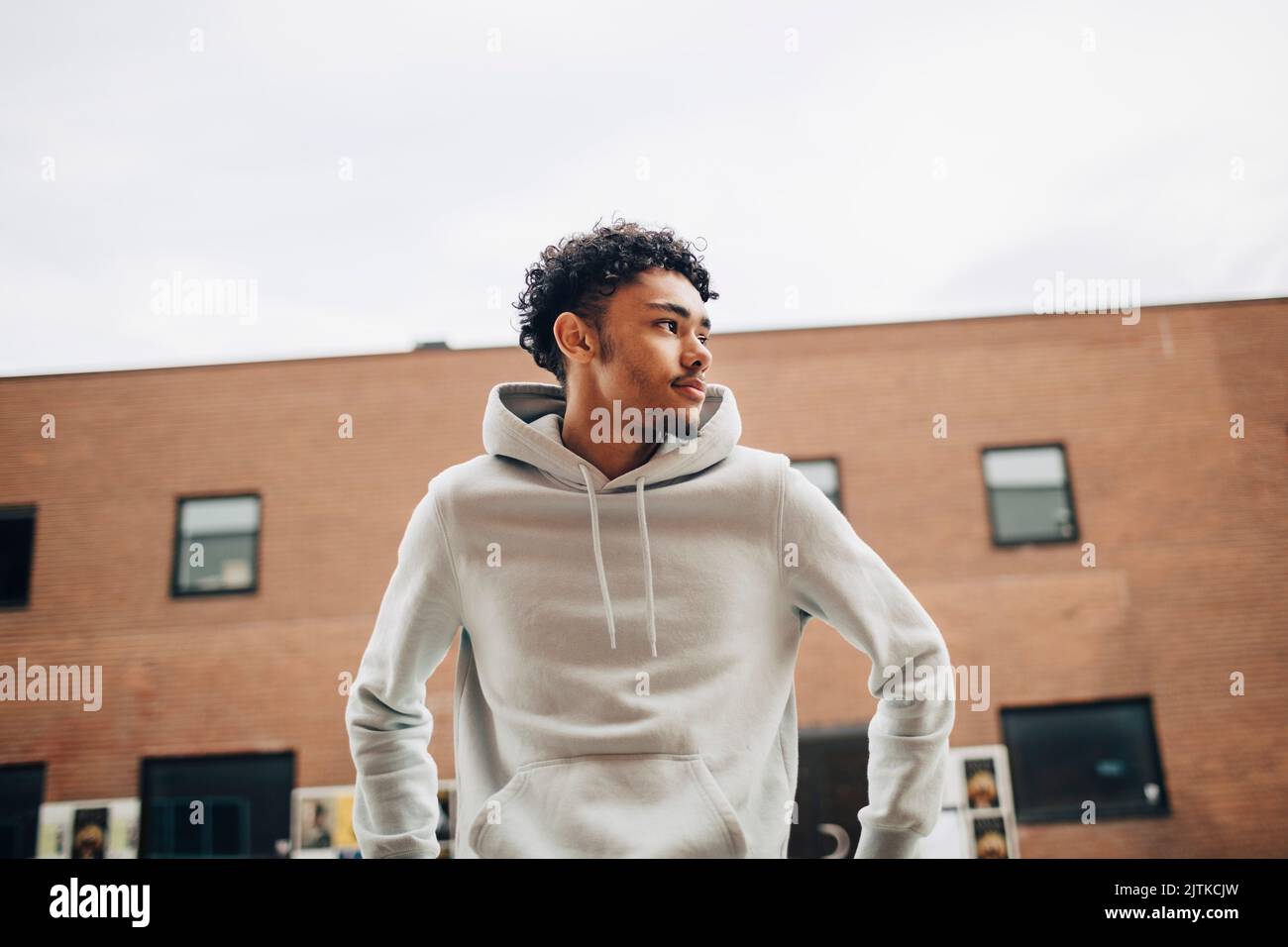 Young man looking away while standing in front of building Stock Photo ...