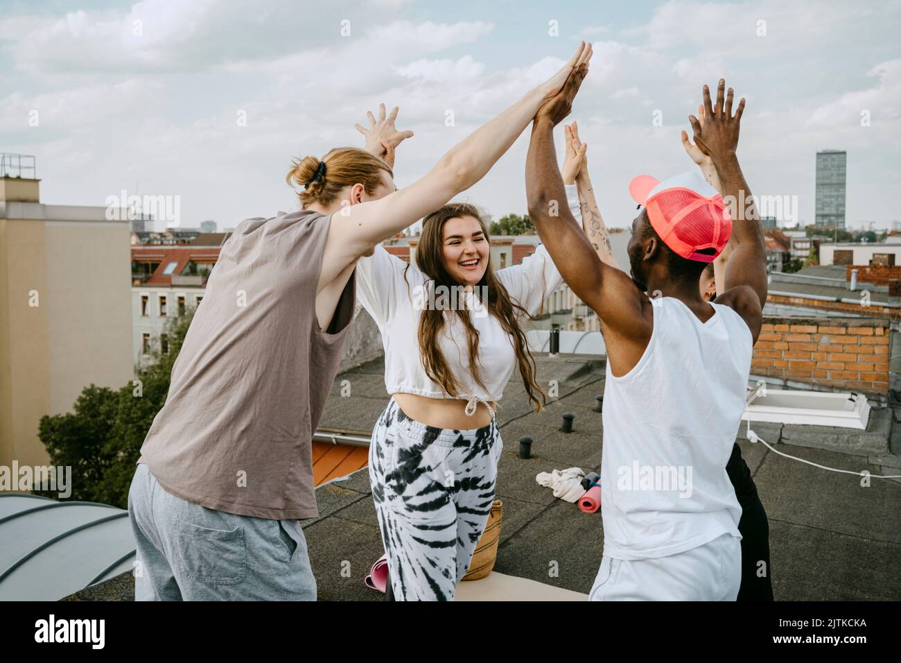 Happy multiracial male and female friends with arms raised giving high ...