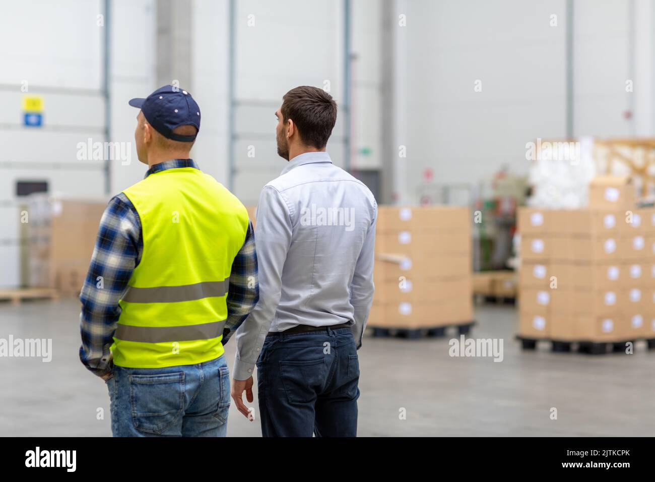worker and businessman walking along warehouse Stock Photo - Alamy