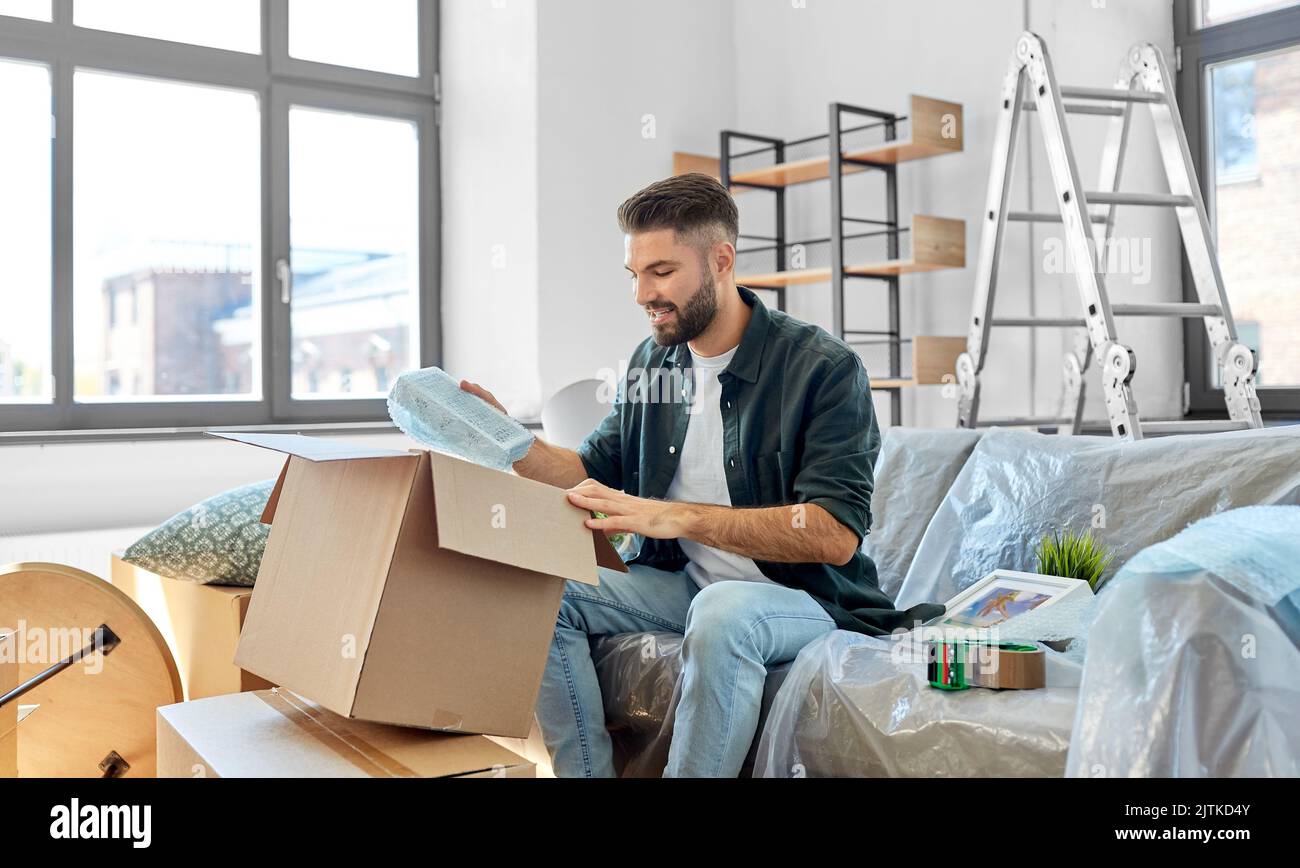 happy man unpacking boxes and moving to new home Stock Photo - Alamy