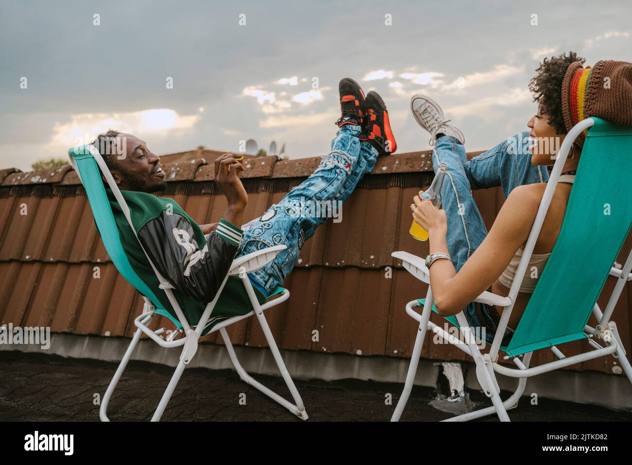 Full length cheerful male and female friends talking while sitting on ...