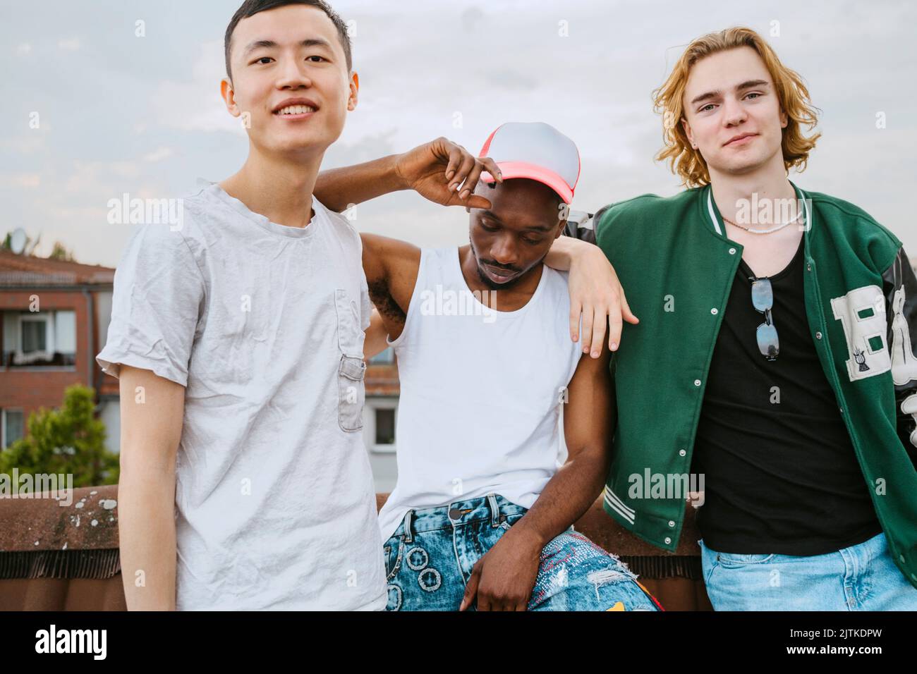 Portrait of smiling young men with friend wearing cap Stock Photo - Alamy