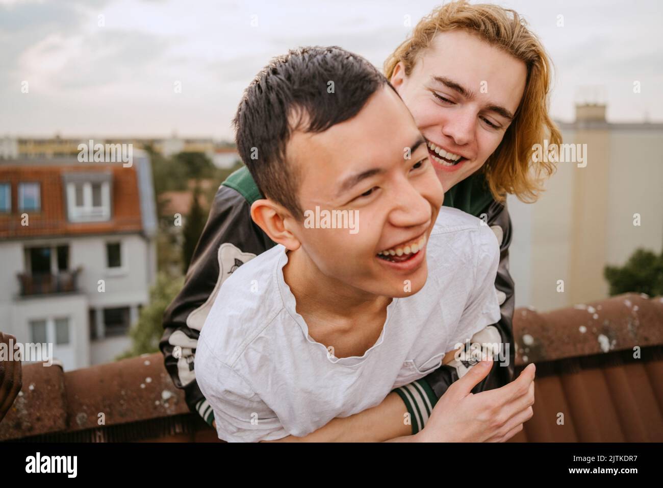 Cheerful young man embracing male friend while enjoying together on ...