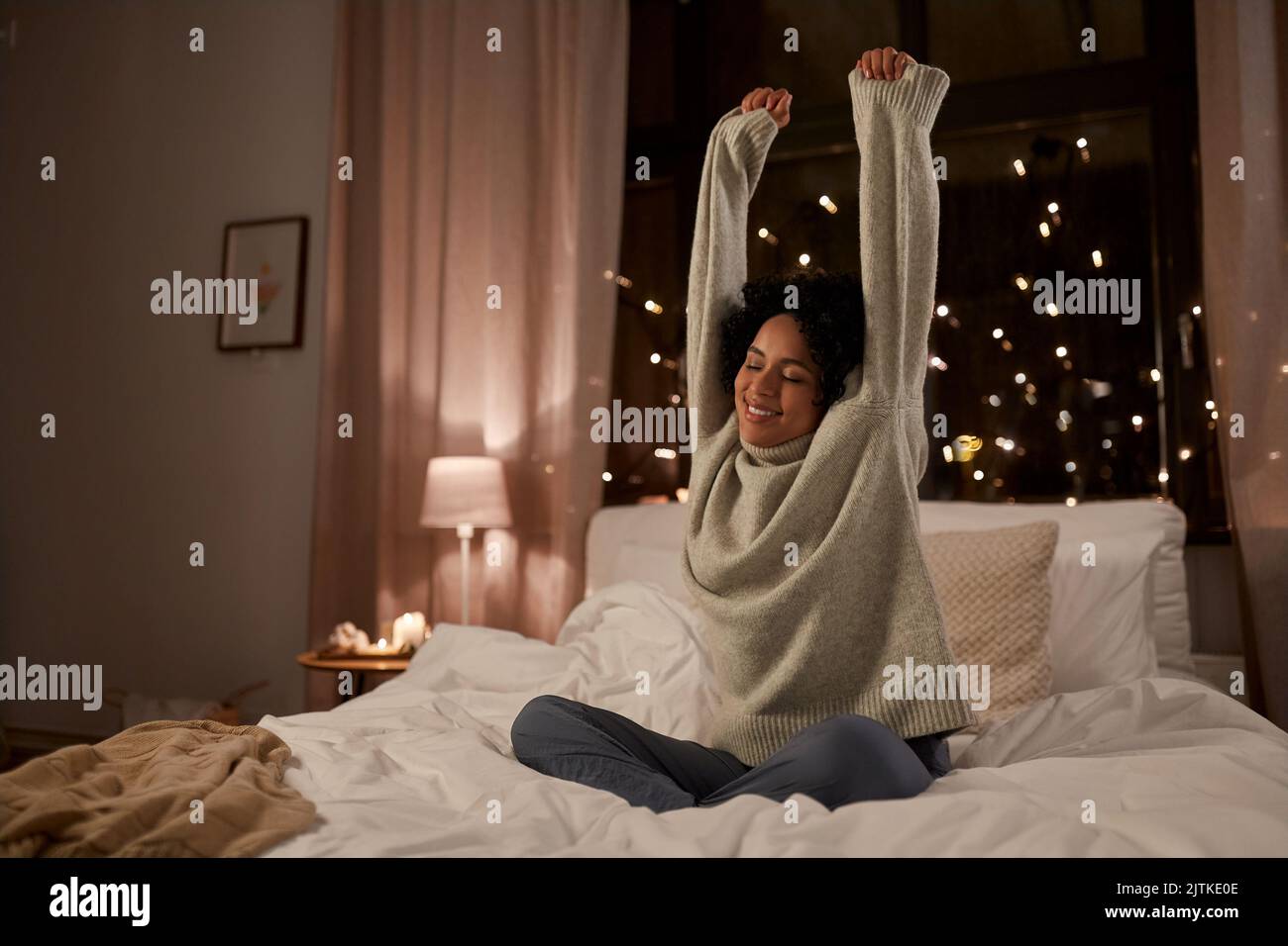woman in sweater stretching in bed at night Stock Photo - Alamy