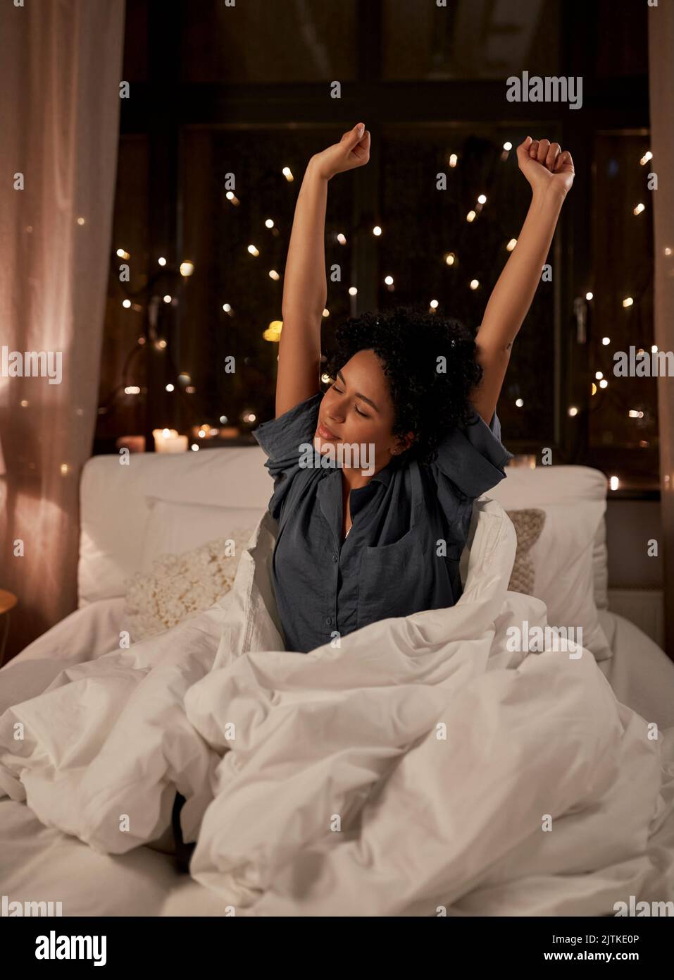 sleepy woman stretching in bed at night Stock Photo - Alamy