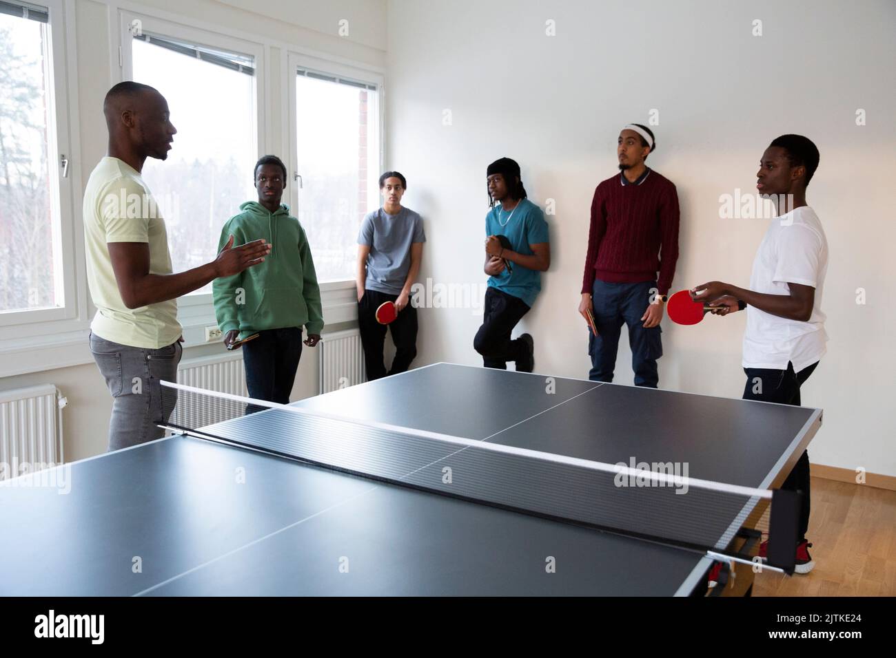 Instructor giving table tennis training to students in games room Stock ...