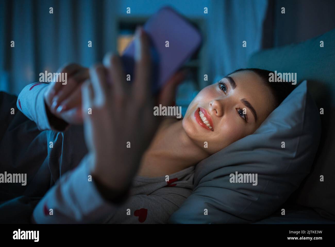 teenage girl with phone lying in bed at night Stock Photo - Alamy
