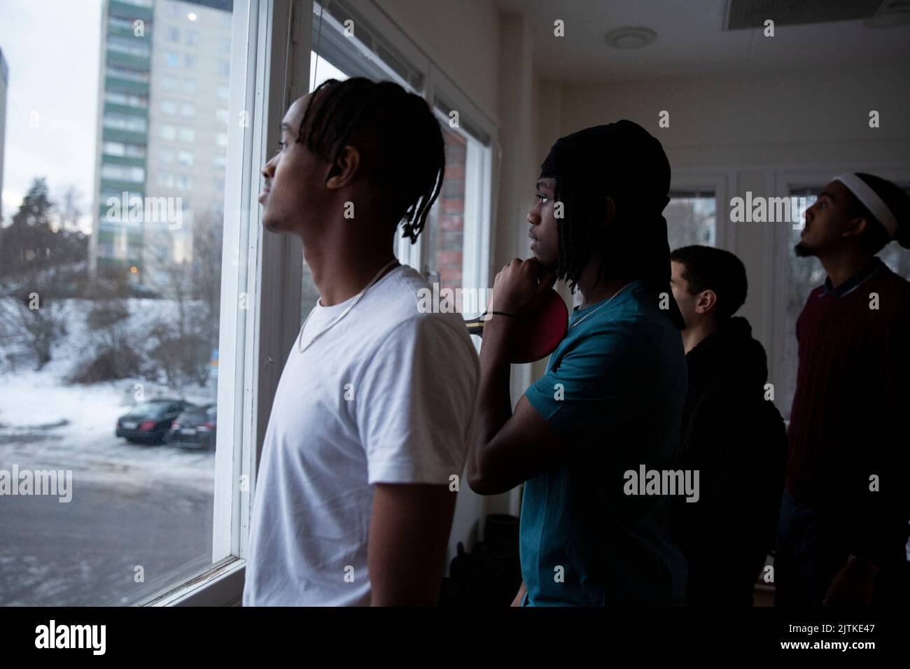 Male friends looking through window in games room Stock Photo - Alamy