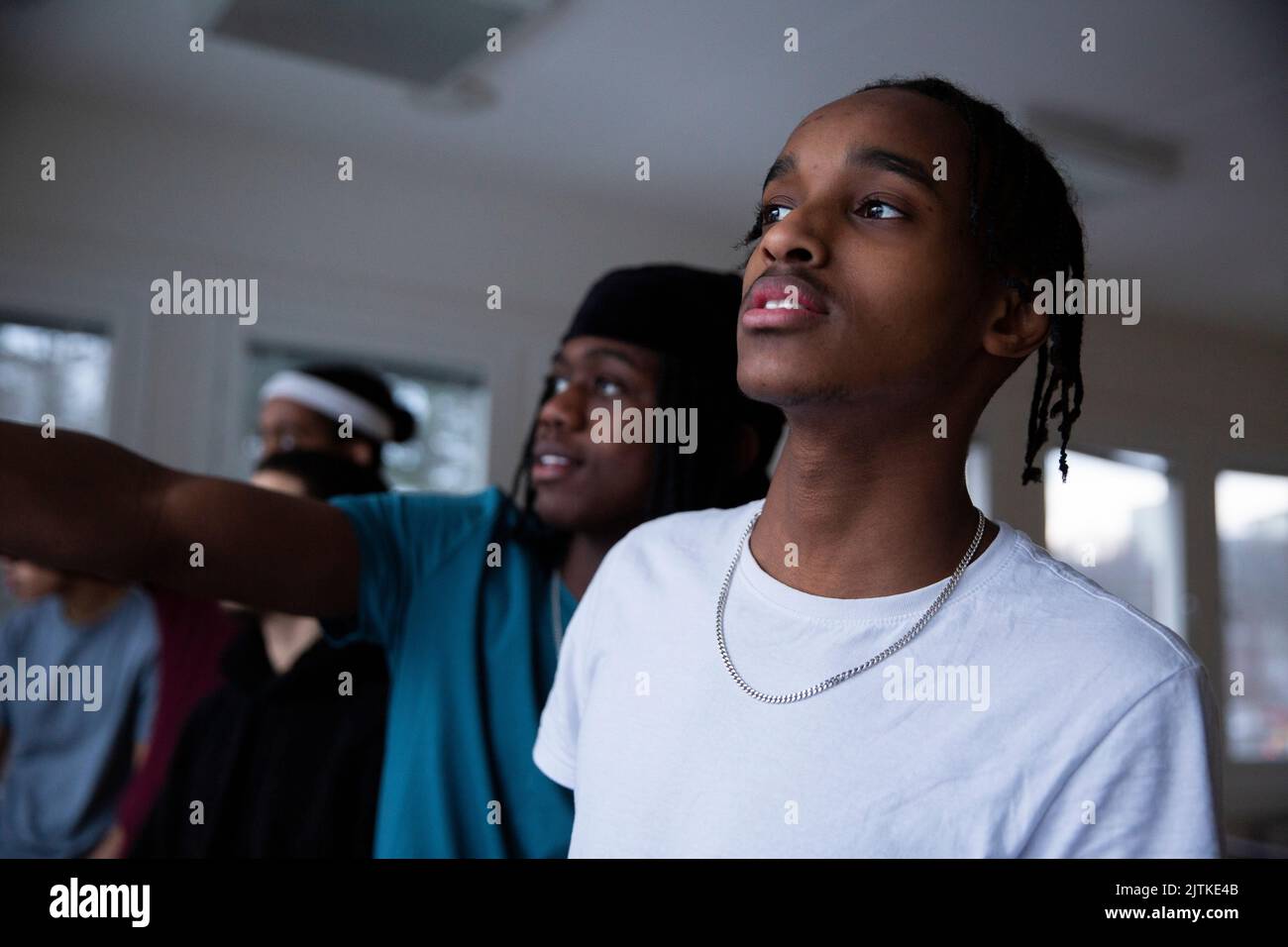 Curious male friends looking away in games room Stock Photo - Alamy