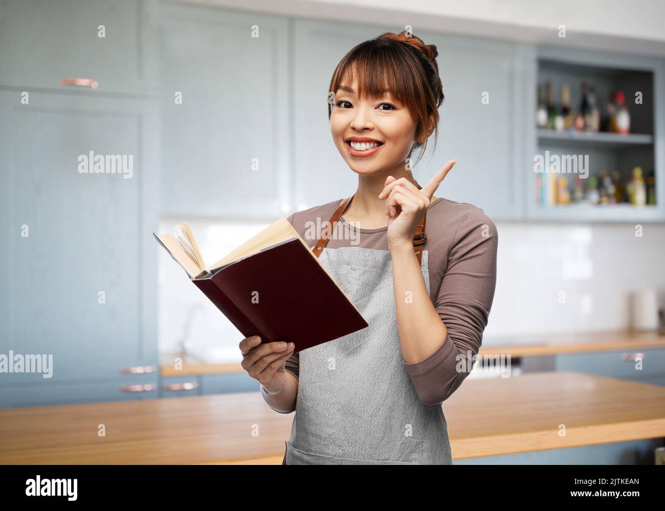 smiling woman in apron with open cook book Stock Photo - Alamy