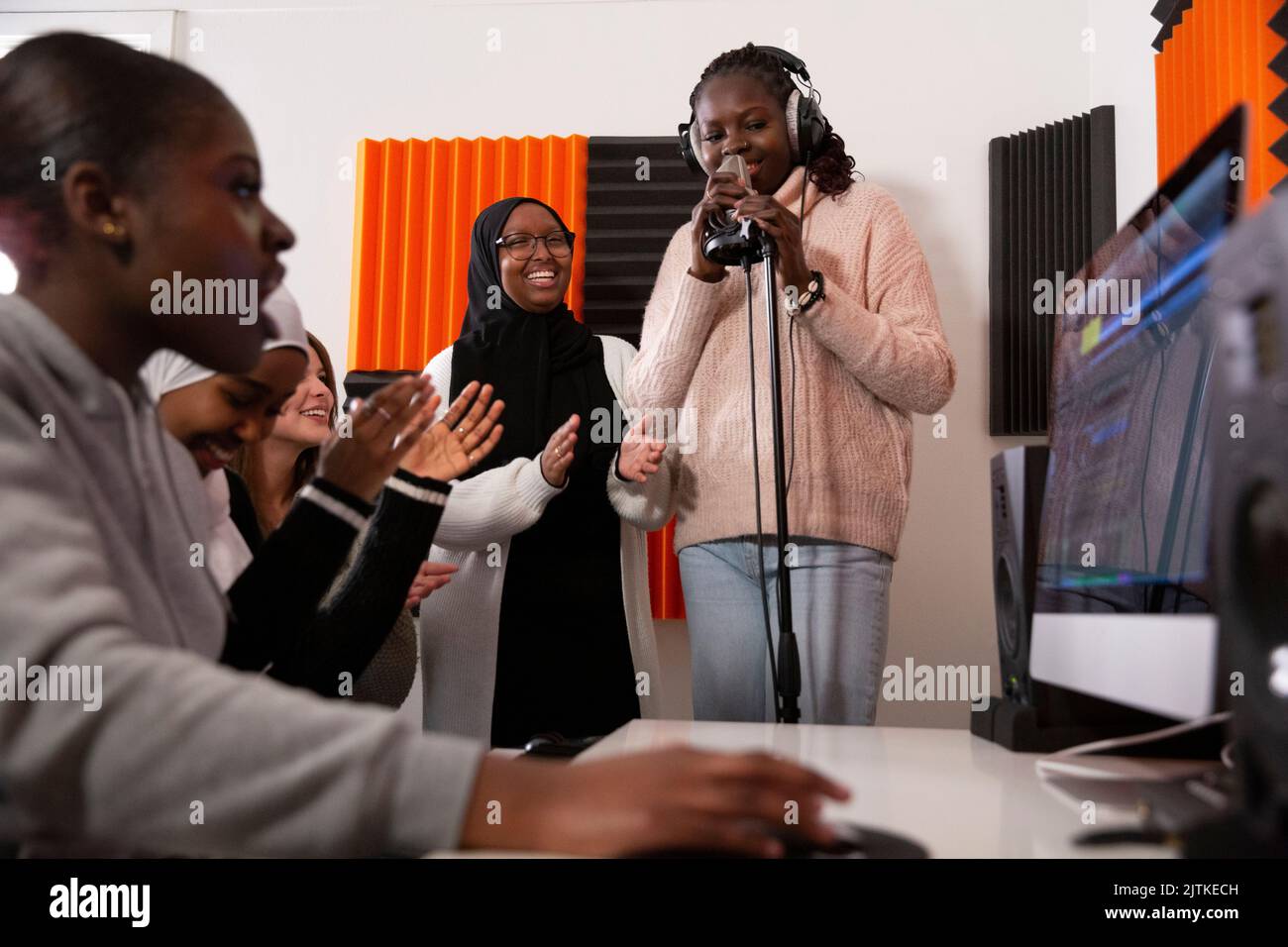 Friends motivating singer recording song on microphone in studio Stock ...