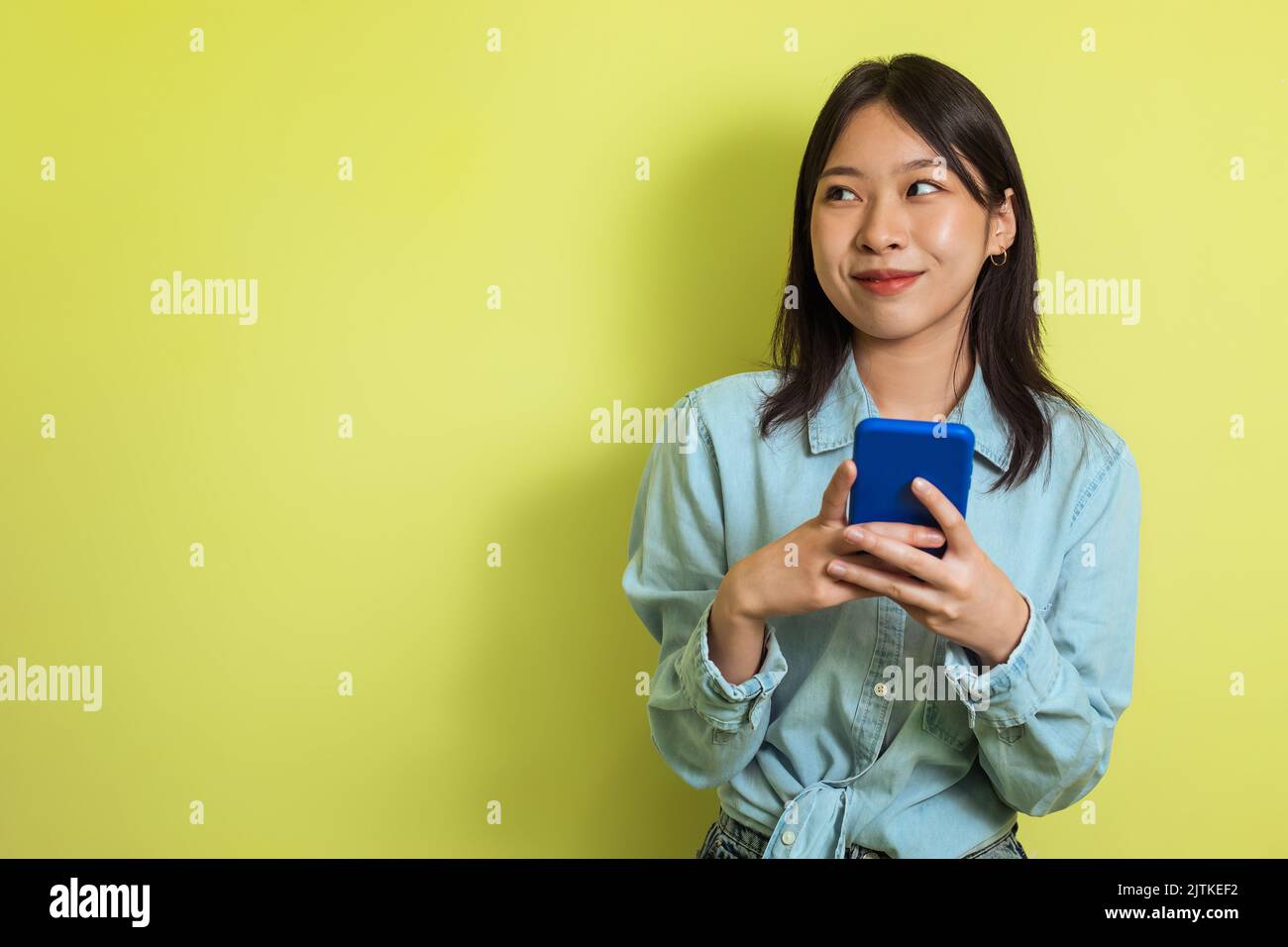 Korean Female Using Mobile Phone Standing Over Yellow Background Stock ...