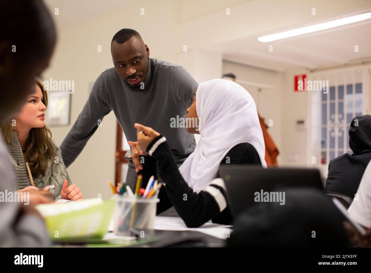 Students discussing with teacher in classroom Stock Photo - Alamy