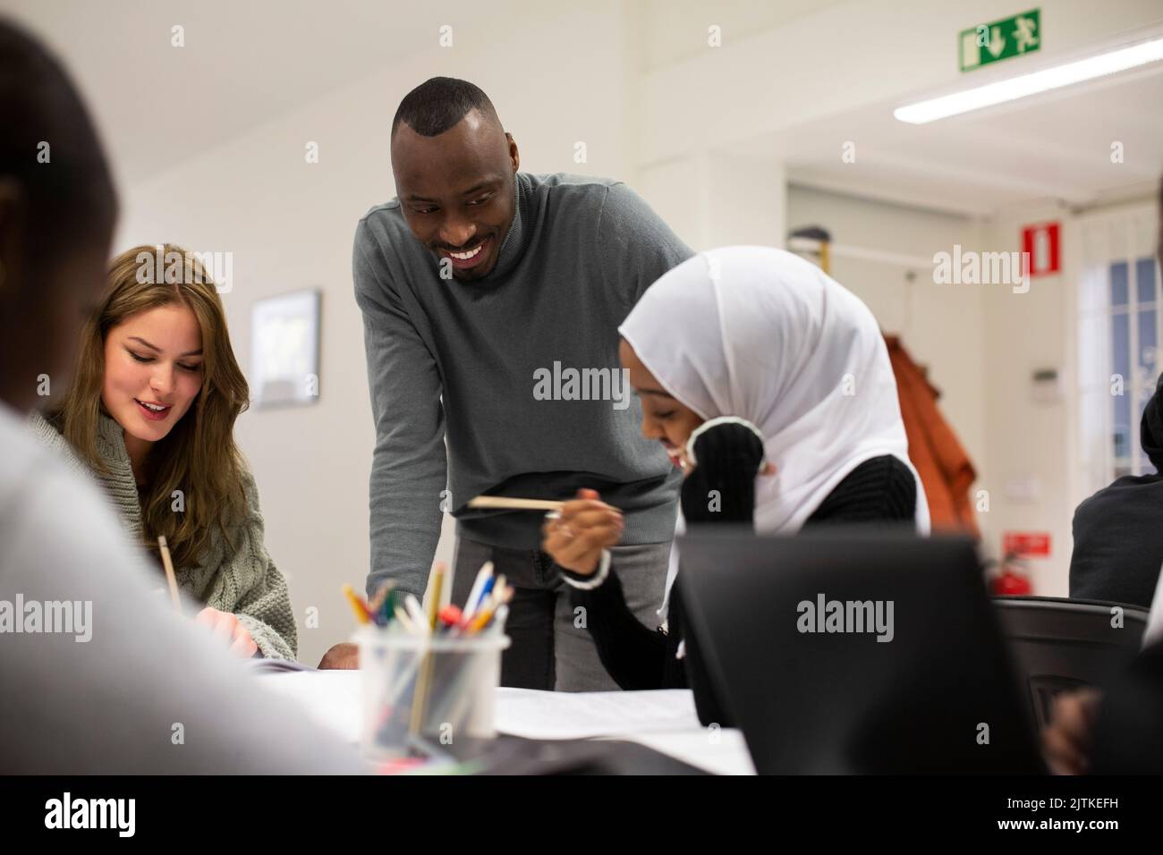 Smiling male teacher talking to students in classroom Stock Photo - Alamy