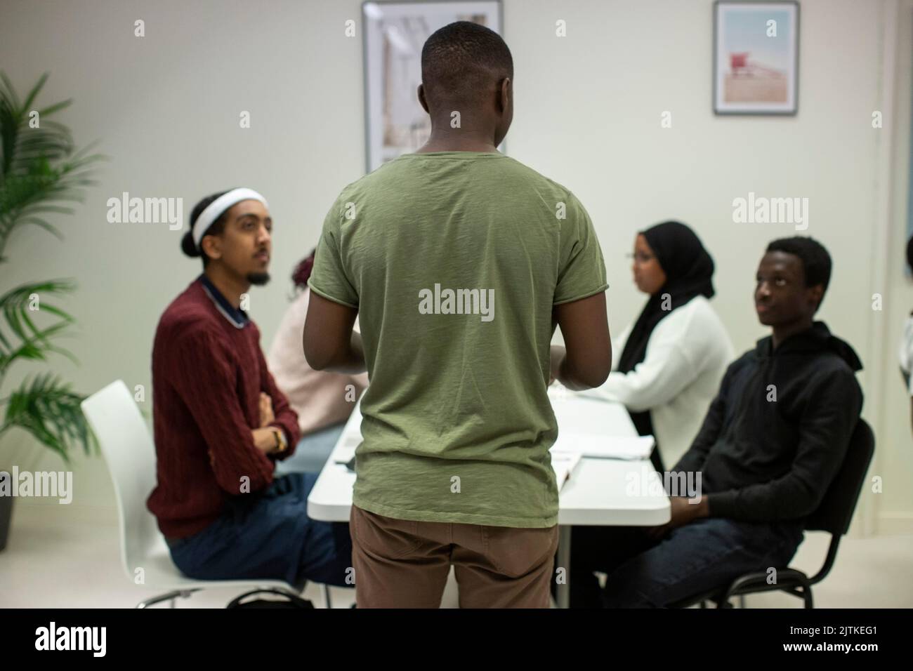 Rear view of male teacher teaching multiracial students in classroom ...