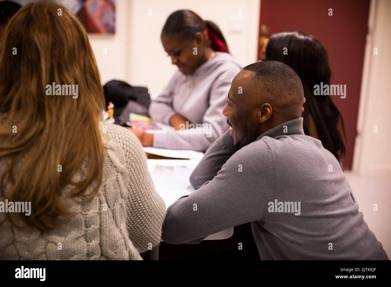 Side view of teacher sitting with students in classroom Stock Photo - Alamy