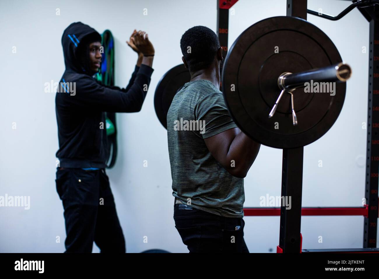 Side view of coach assisting athlete while picking up barbell during ...