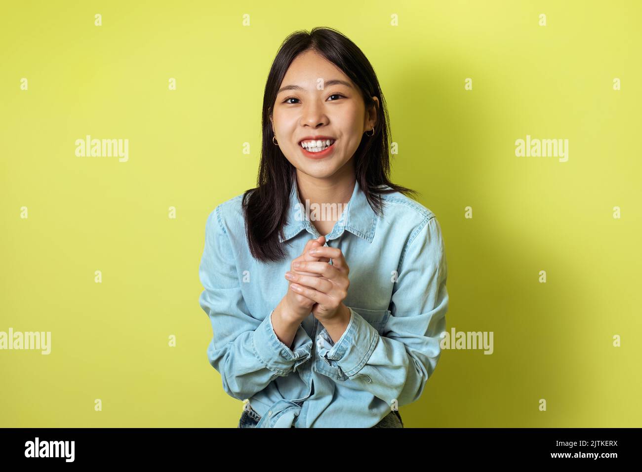 Happy Korean Woman Holding Hands Together Posing Over Yellow Background ...