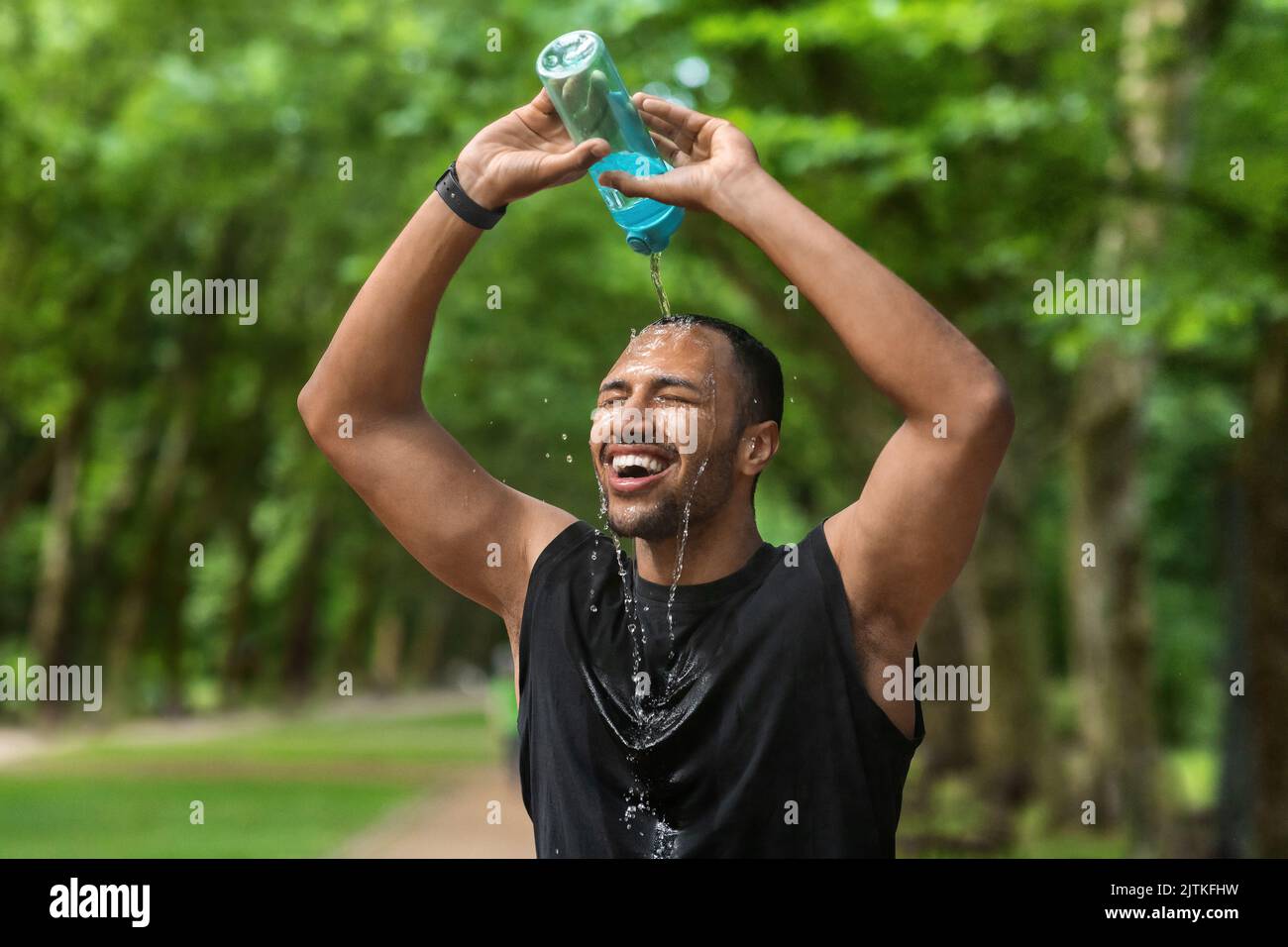 Exhausted african american sportsman splashing water all over his head ...