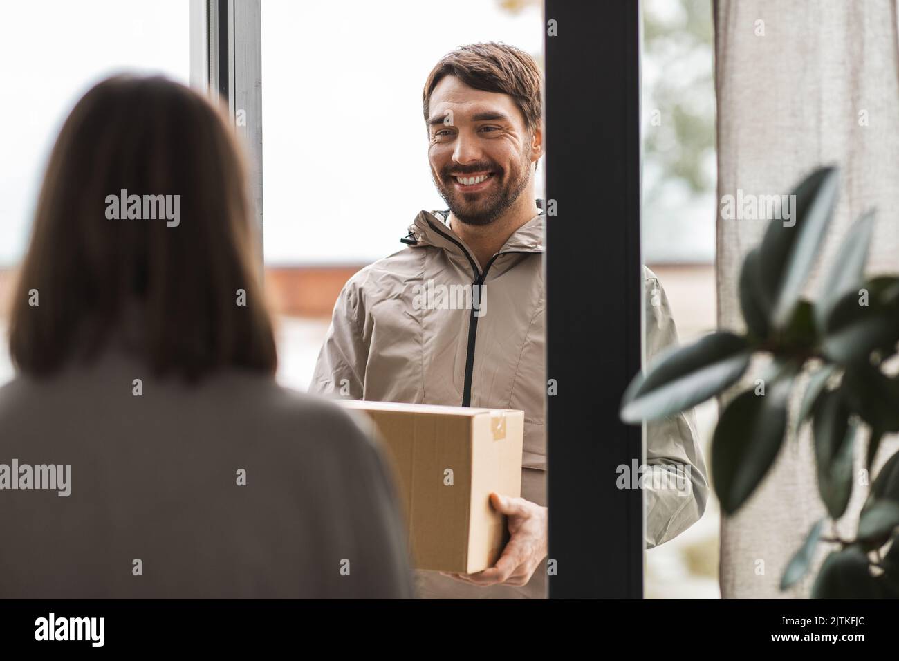 delivery man with parcel box and customer at home Stock Photo - Alamy