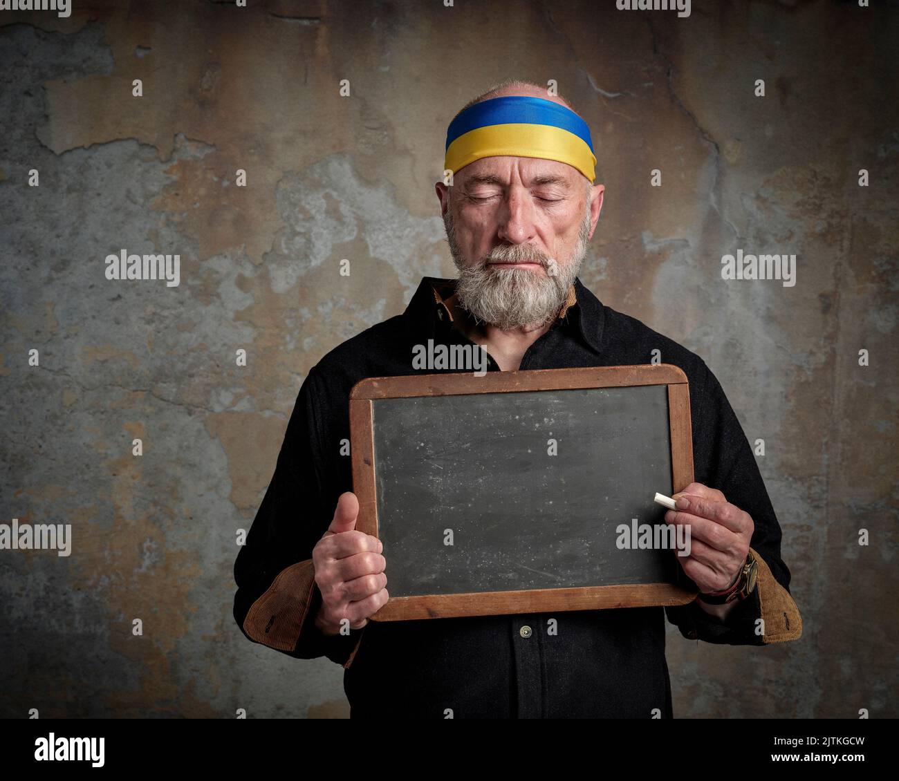 blank slate blackboard held by a senior man wearing blue and yellow ...