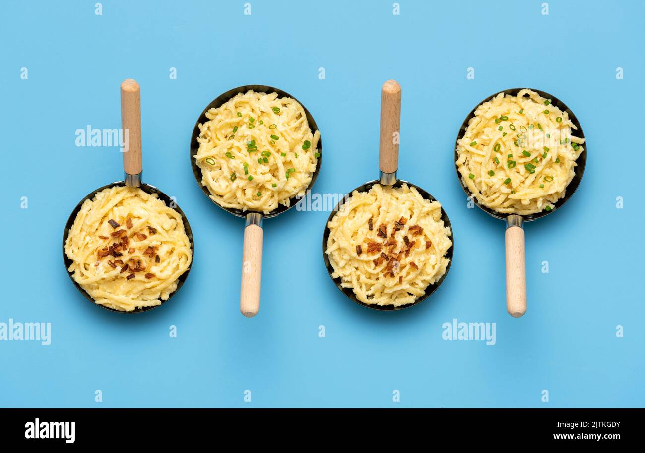 Above view with small pans of spaetzle on a blue table. German dish ...