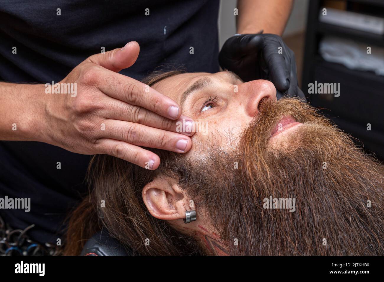 Barber applying cream on client's beard Stock Photo - Alamy