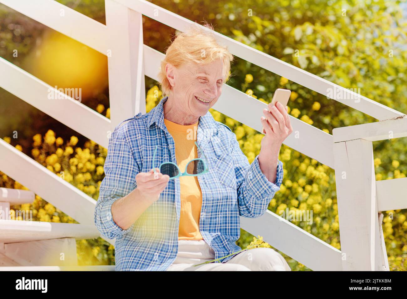 Mature woman sitting alone on the terrace of beach cafe and using ...