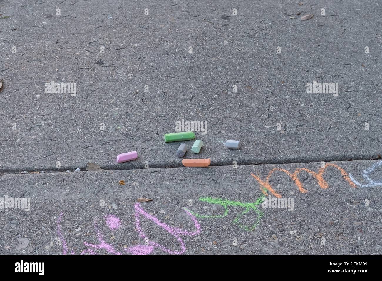 Colorful chalk and a child's scribblings left behind on a city sidewalk ...