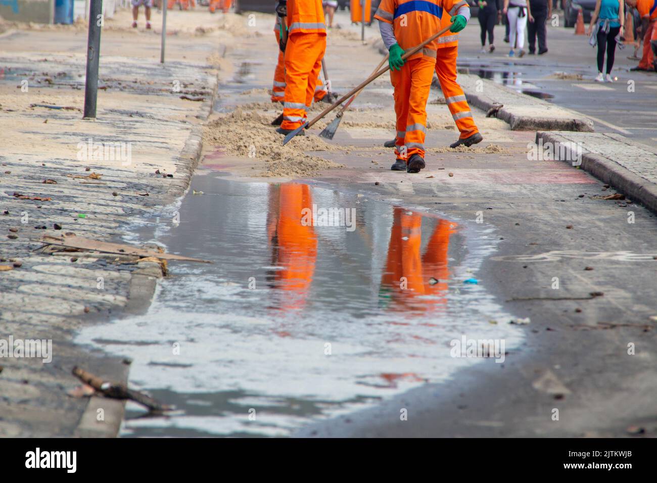 cleaning workers removing sand from the Leblon beach boardwalk in Rio ...