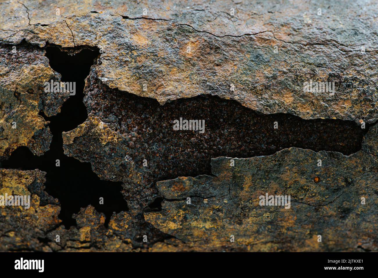 Hole with sharp ages in a rusted peeling iron pipe texture with grooves ...