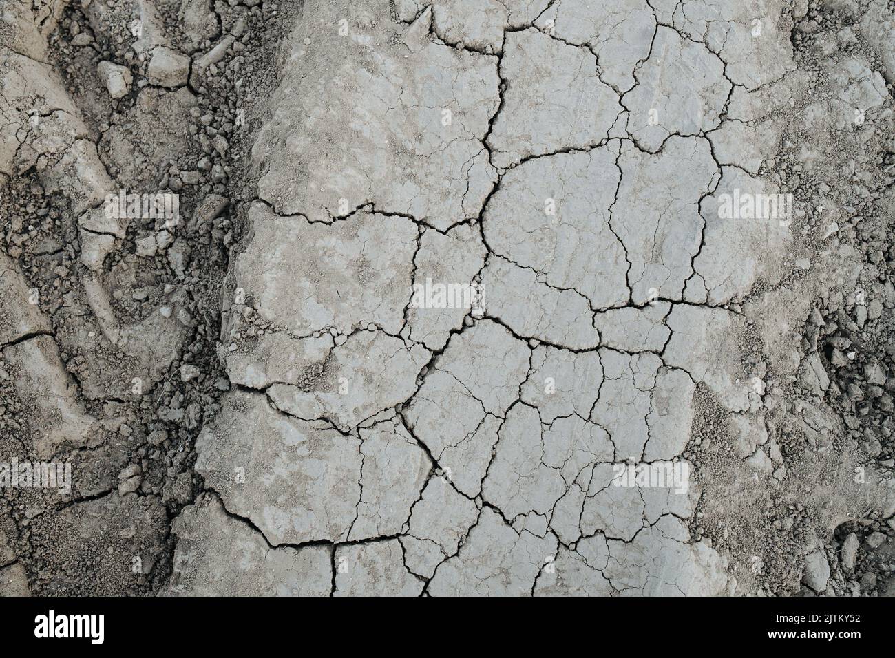 Cracked grey dry dirt texture with tire prints on sides. Top view Stock ...