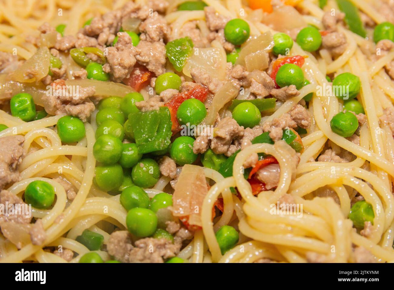 pasta, ground beef, peas, green peppers and chopped tomatoes over a pan ...
