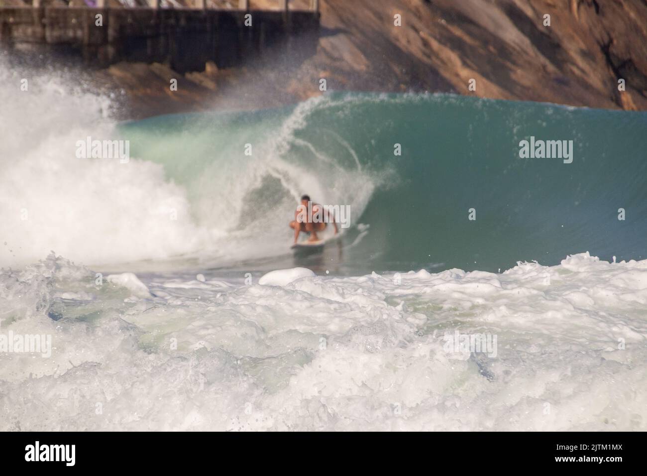 white foam of a wave at leblon beach with defocused surfer in the ...