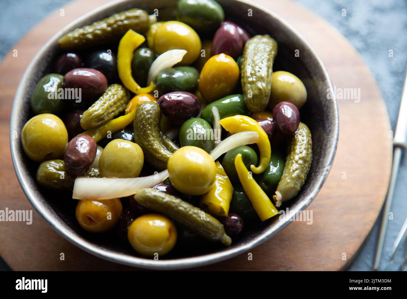 Pickled gherkins, onion, chilli and various types of olives in a bowl ...