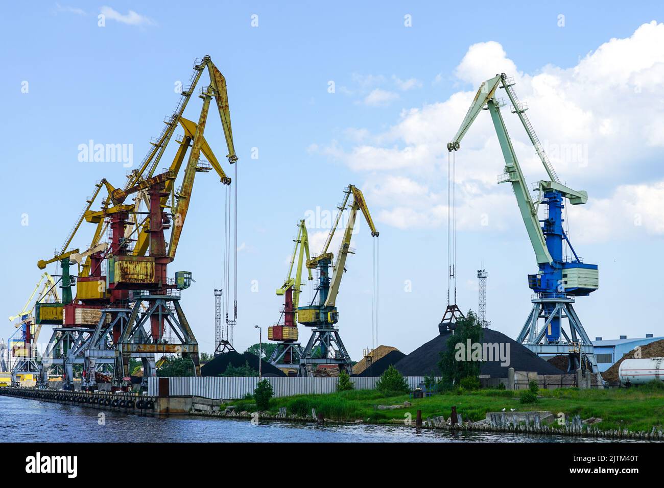Bulk cargo terminal in port with many shore cranes and piles of coal ...