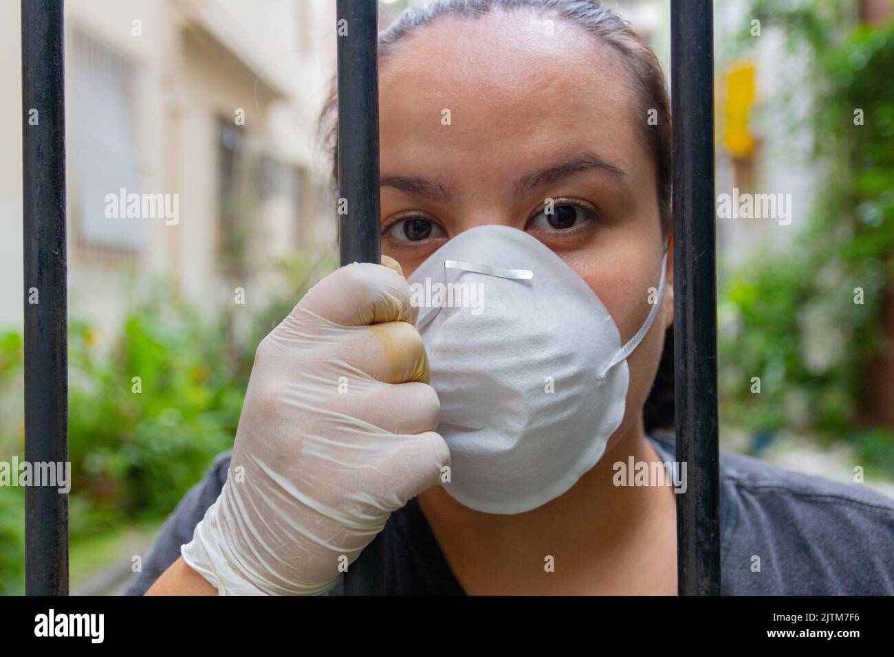 white woman with mask and glove behind a grid during coronavirus ...