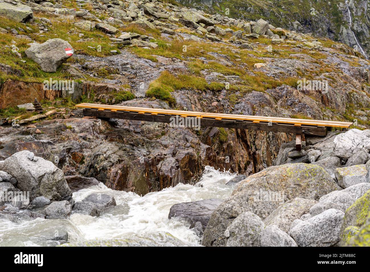 A small wooden bridge over a wild alpine river Stock Photo - Alamy
