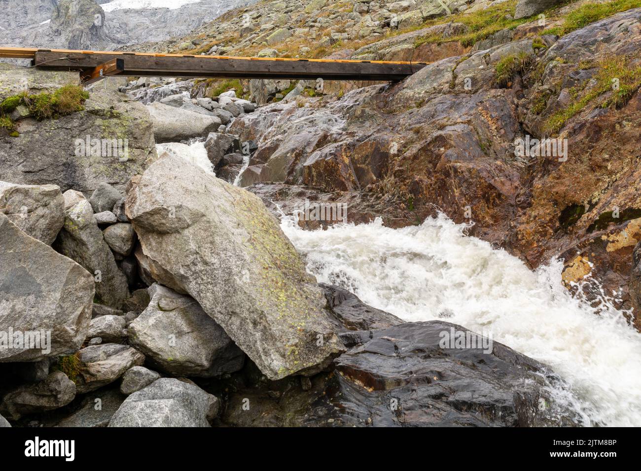 A small wooden bridge over a wild alpine river Stock Photo - Alamy