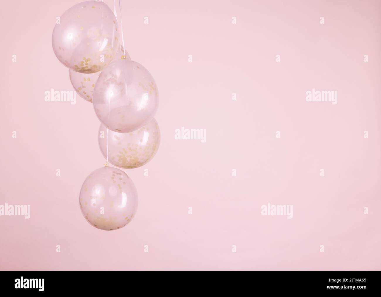 A monochromatic pink confetti clear balloons against a light pink ...