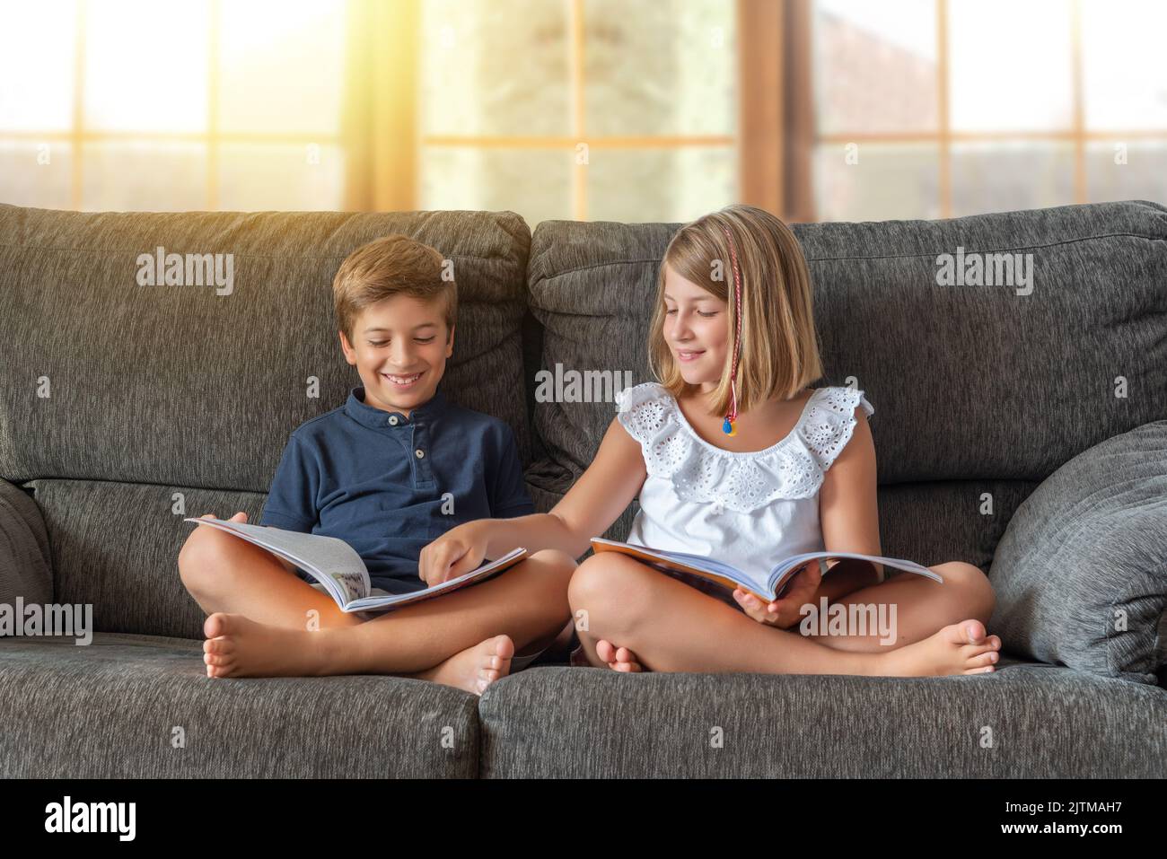 Two children reading and studying on the sofa at home. Back to school ...