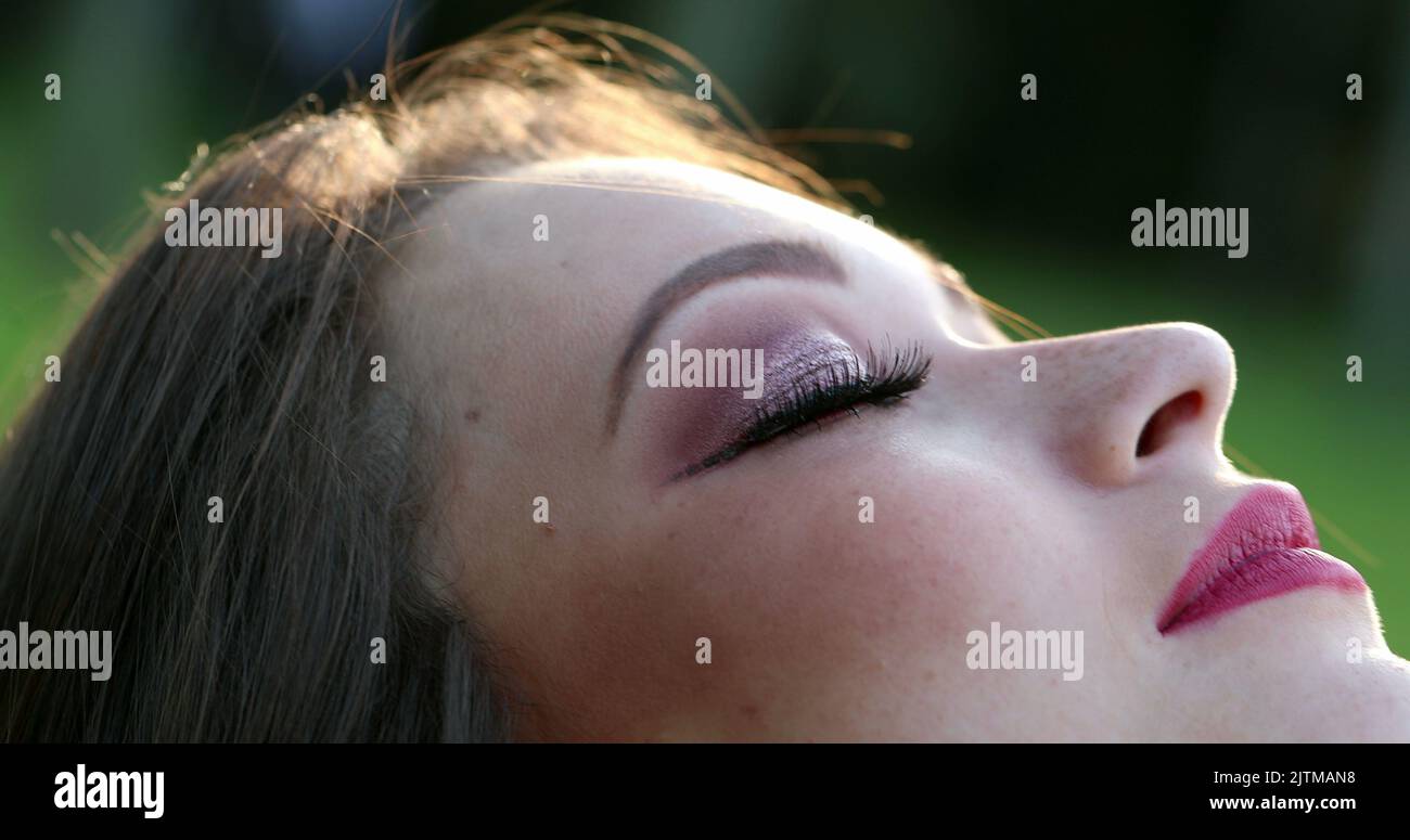 Attractive young woman face opening eyes looking at the sky with hope ...