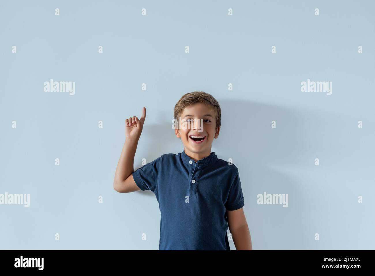 Smiling Caucasian boy pointing his finger upwards. Young boy having an ...