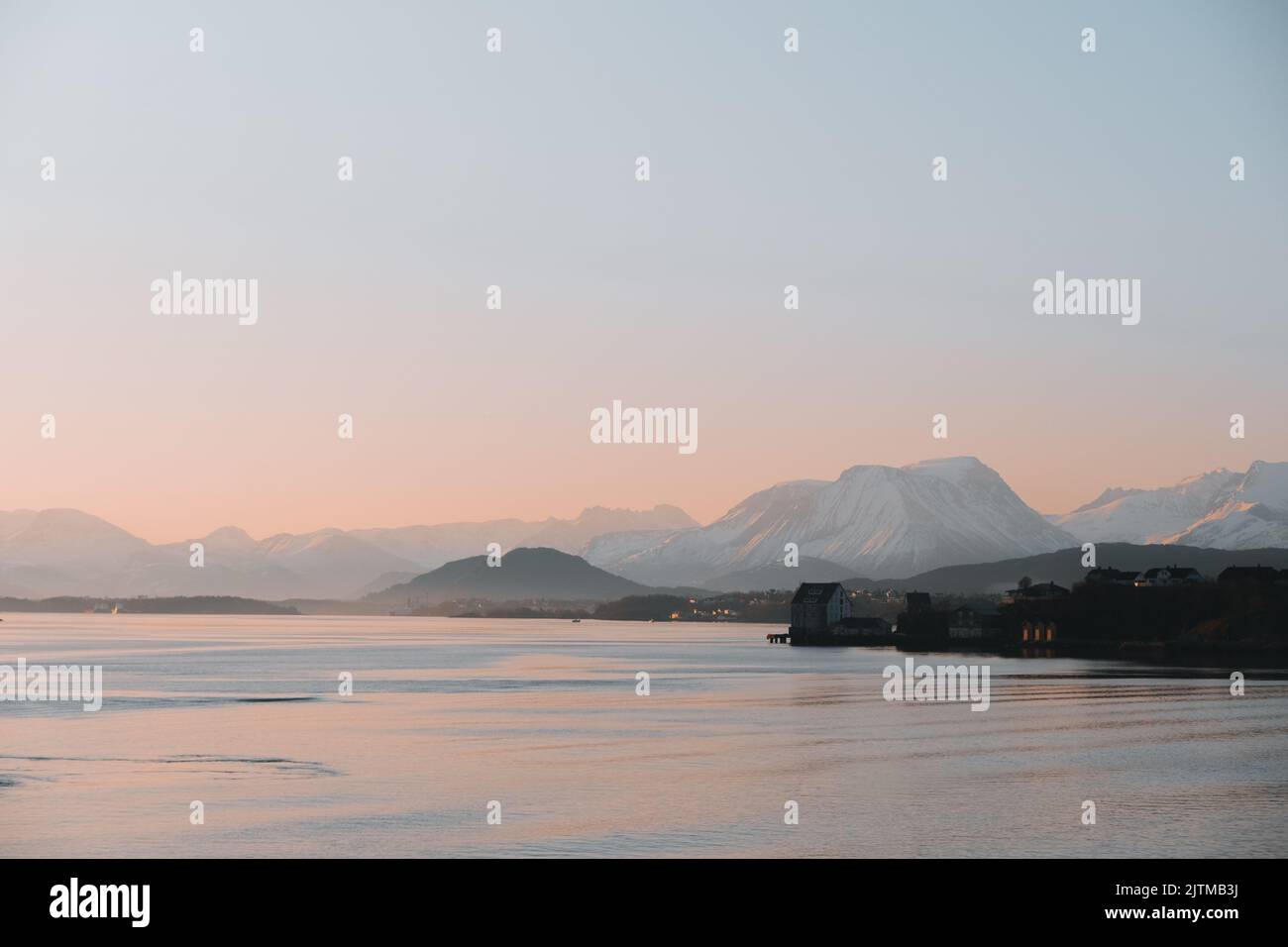 The calm lake and mountains under the sunset sky in Alesund, Norway ...